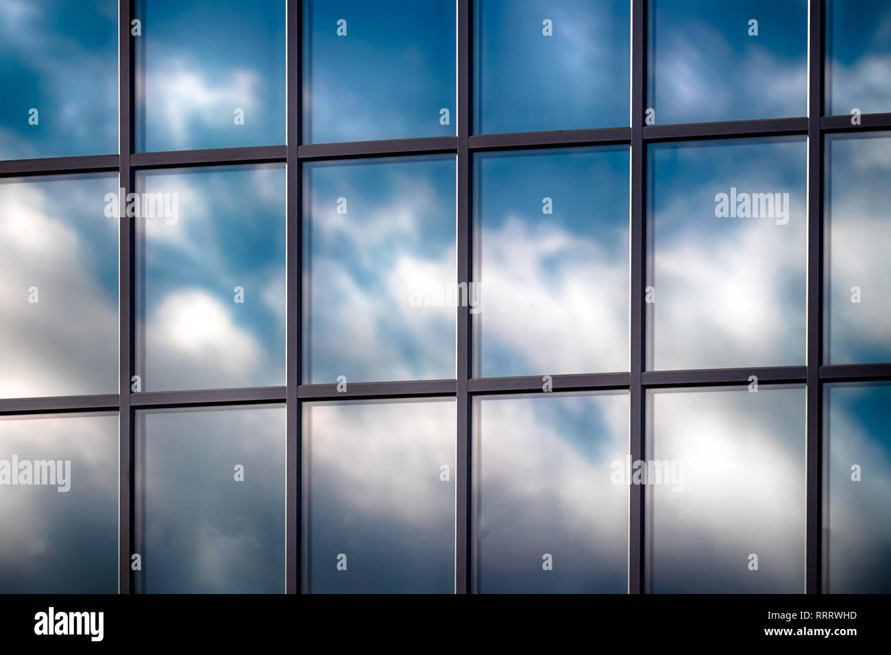 Abstract skyscraper glass window with clouds in reflection and blue sky ...