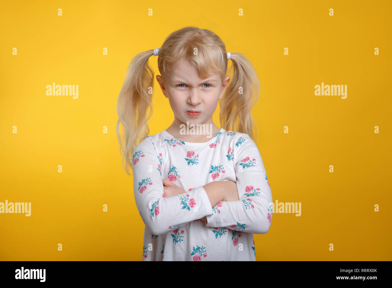 Cute grumpy angry Caucasian blonde girl with blue eyes in white dress ...