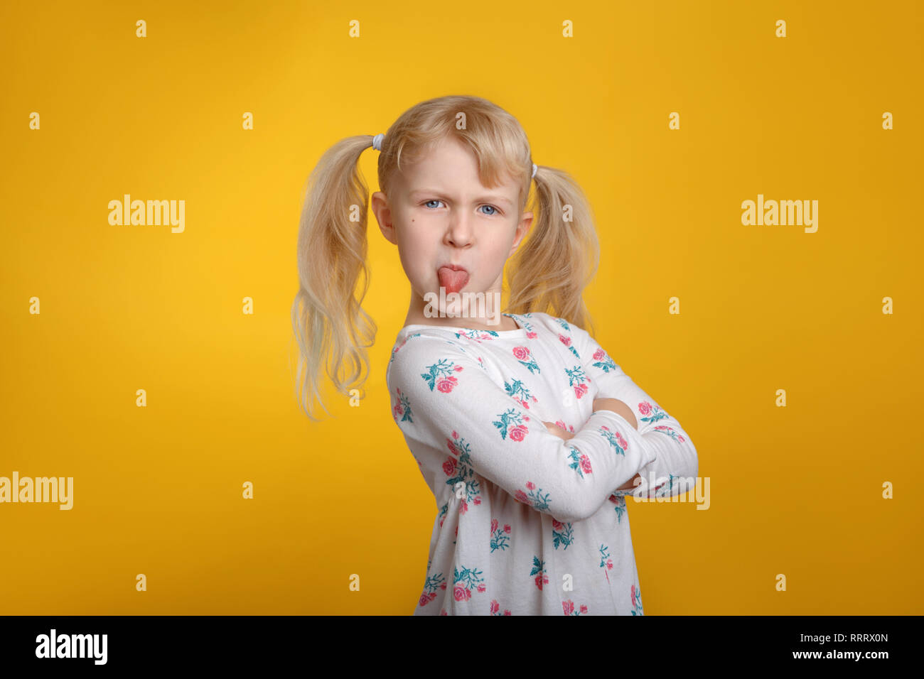 Grumpy angry Caucasian blonde girl with blue eyes in white dress posing ...