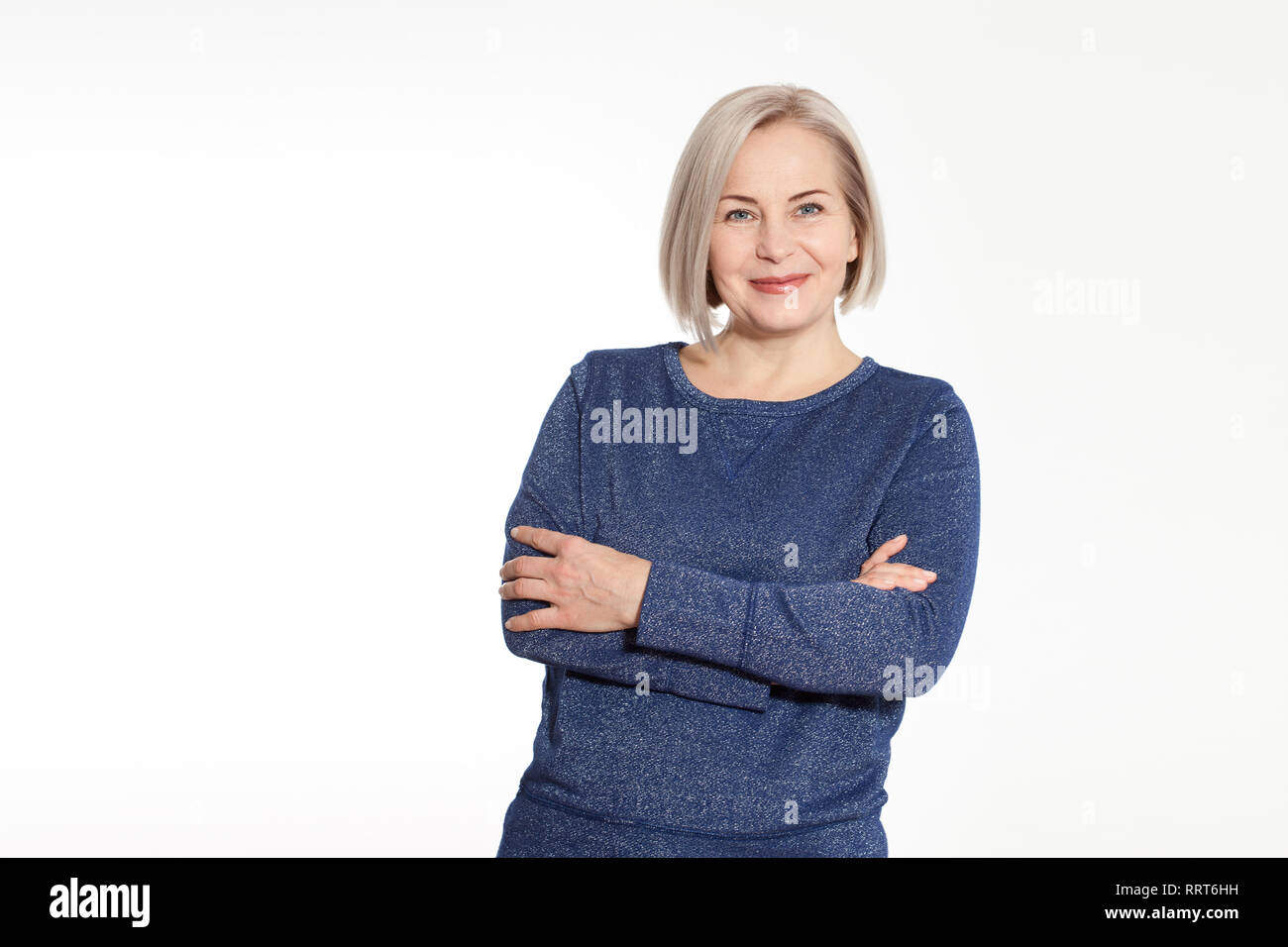 Attractive middle aged woman with folded arms emotionally posing in studio on white background ...