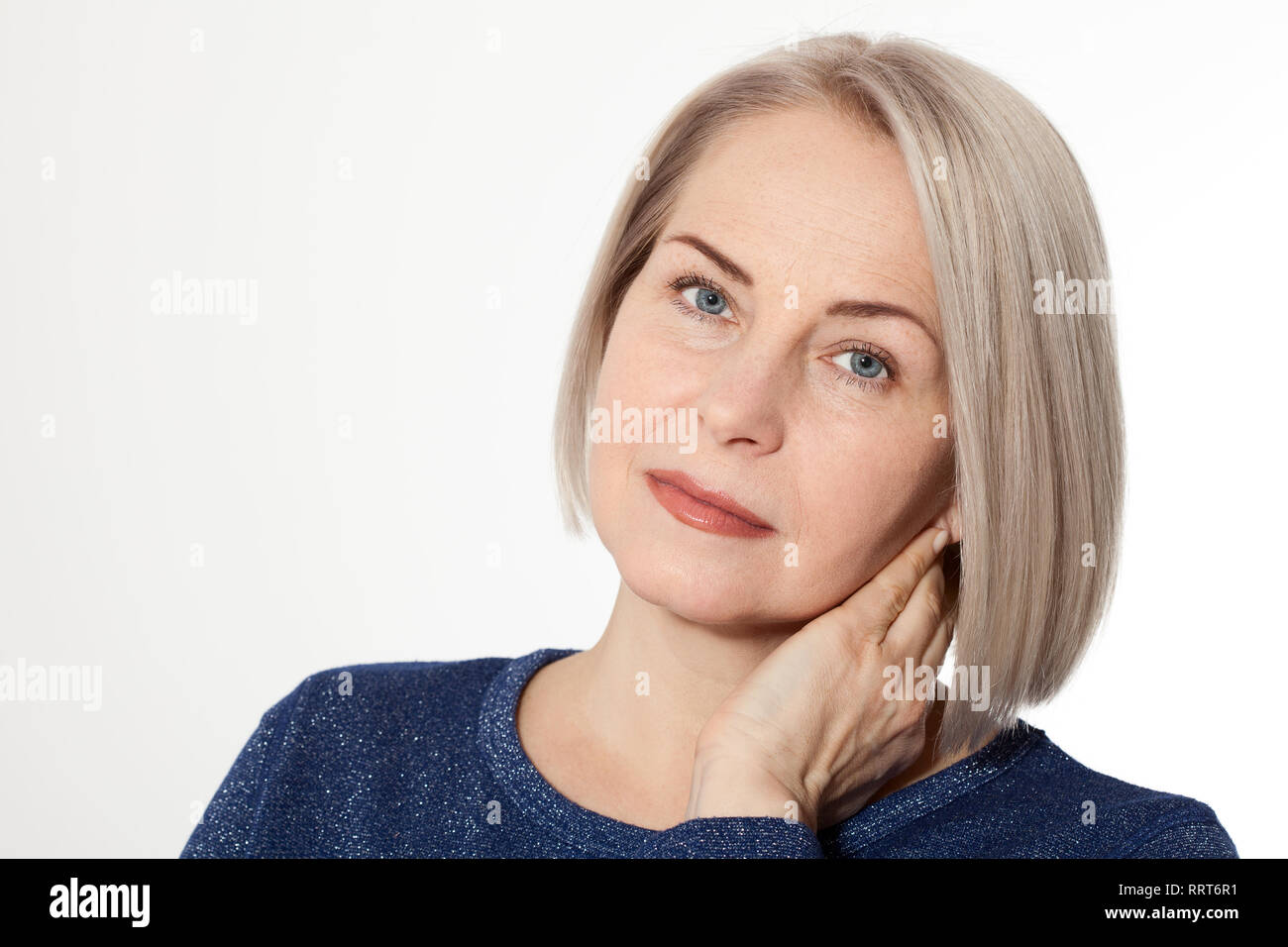 Attractive middle aged woman with folded arms emotionally posing in studio on white background ...