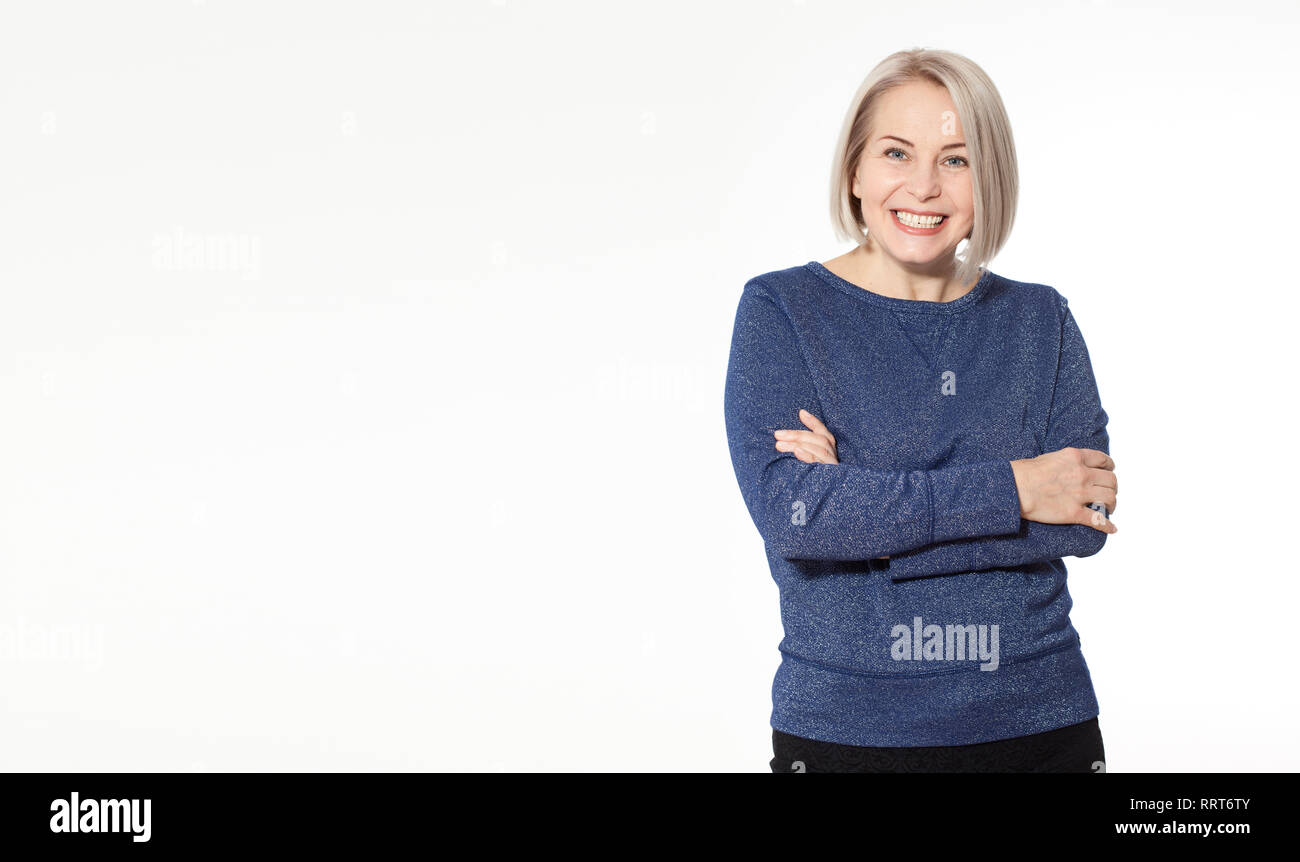 Attractive middle aged woman with folded arms emotionally posing in studio on white background ...