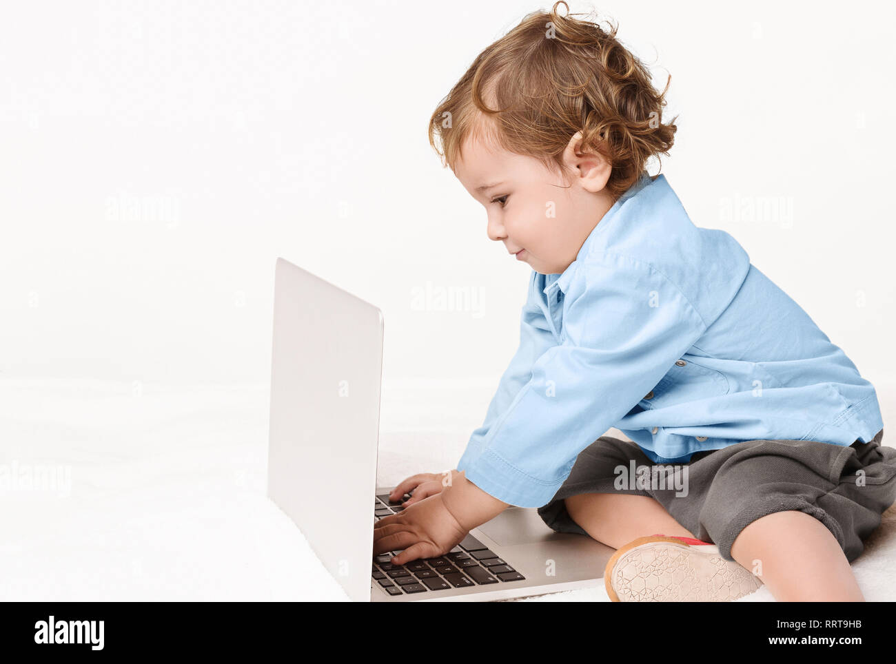 Cute baby boy typing on laptop keyboard Stock Photo - Alamy