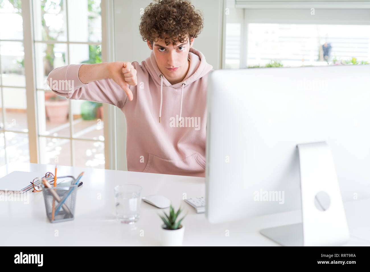 Young student man using computer with angry face, negative sign showing ...