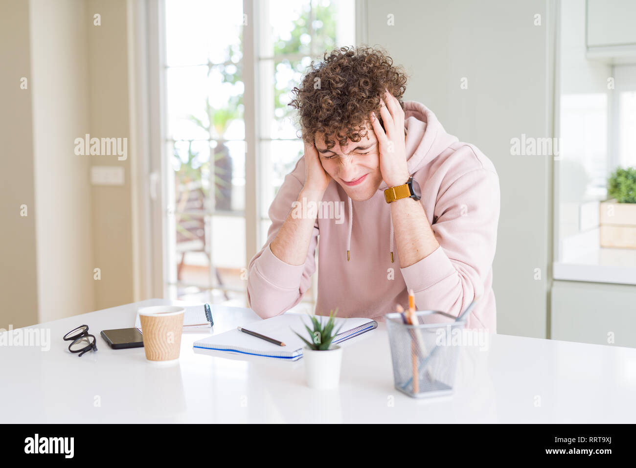 Young student man writing on notebook and studying suffering from ...