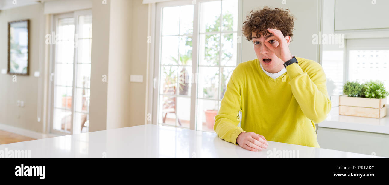Wide angle shot of young handsome man at home doing ok gesture shocked ...