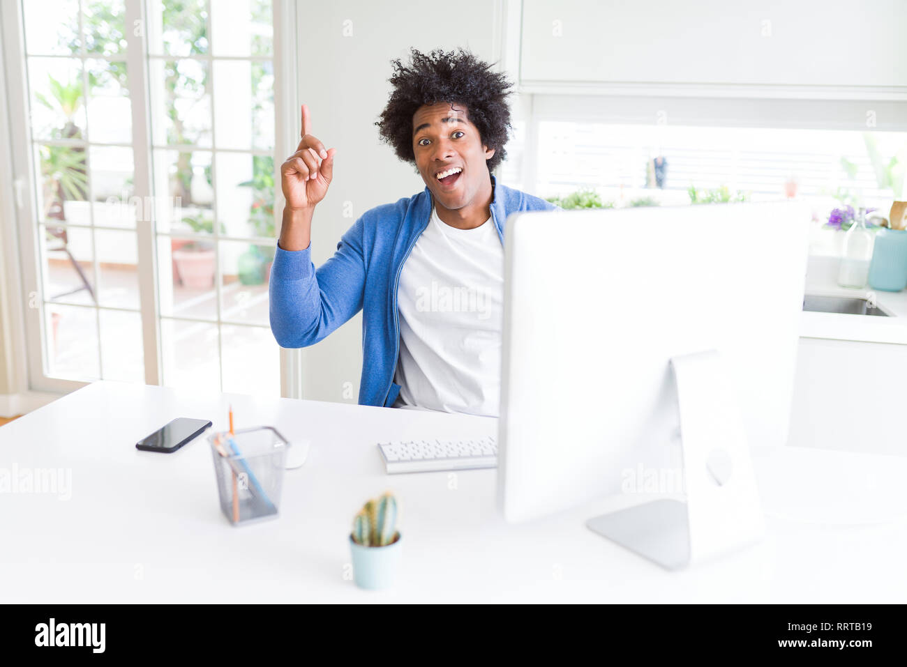 African American man working using computer pointing finger up with ...