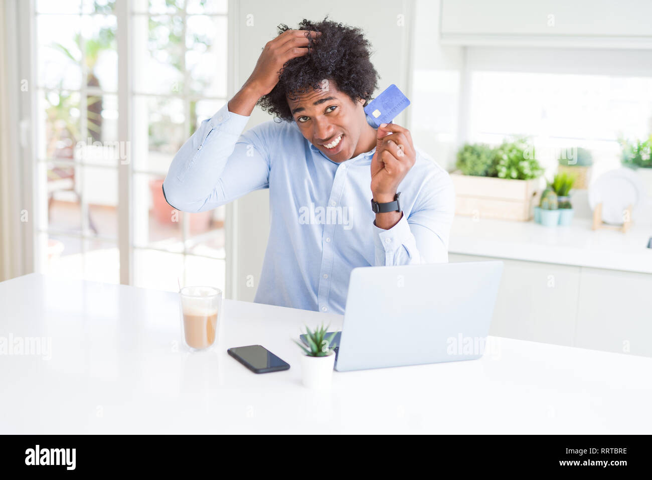 African American man using laptop and shopping online with credit card ...