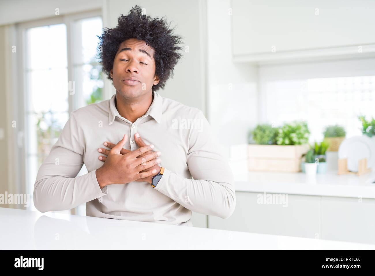 African American man at home smiling with hands on chest with closed ...