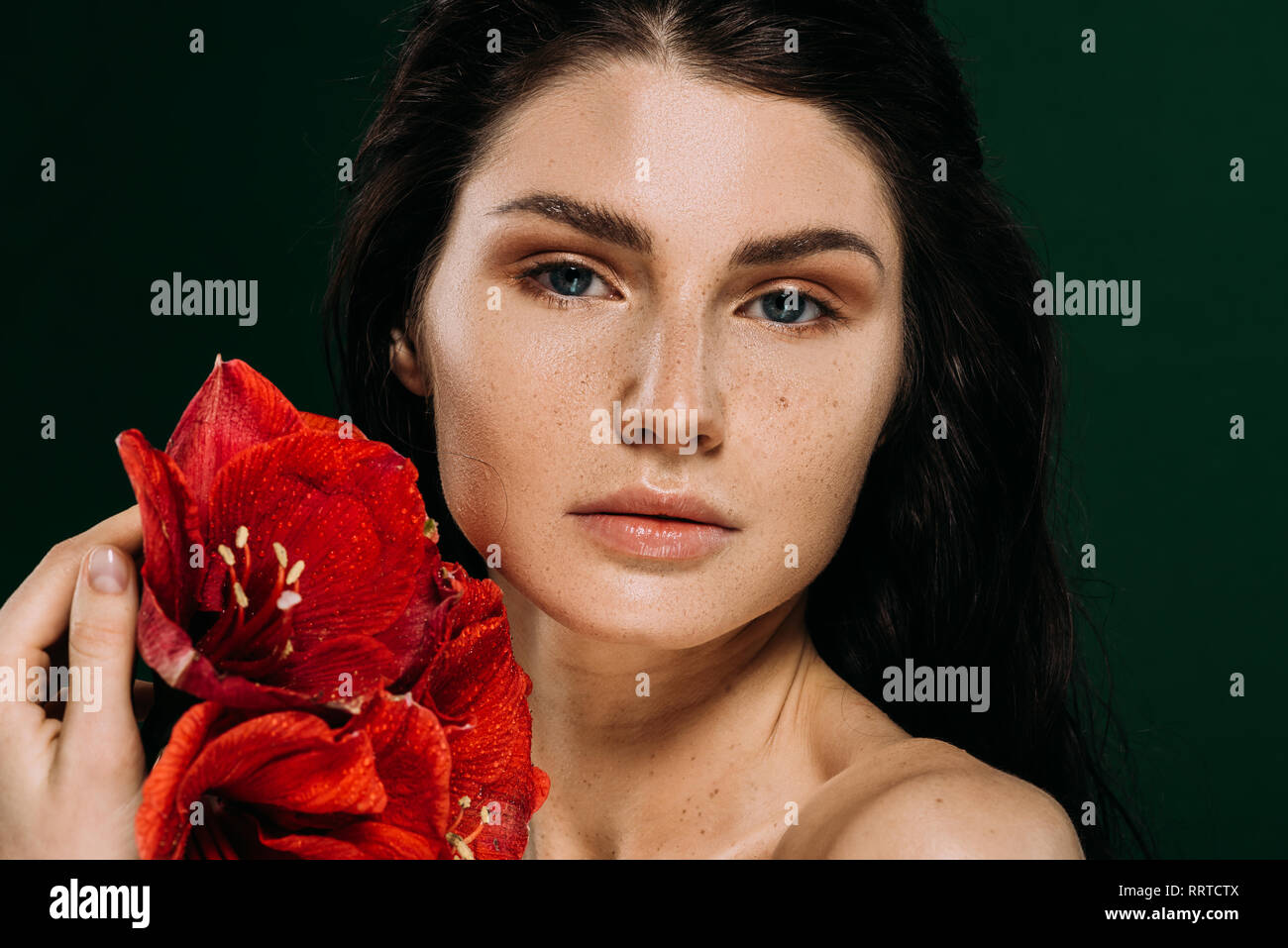 beautiful woman with freckles on face posing with red amaryllis flowers ...