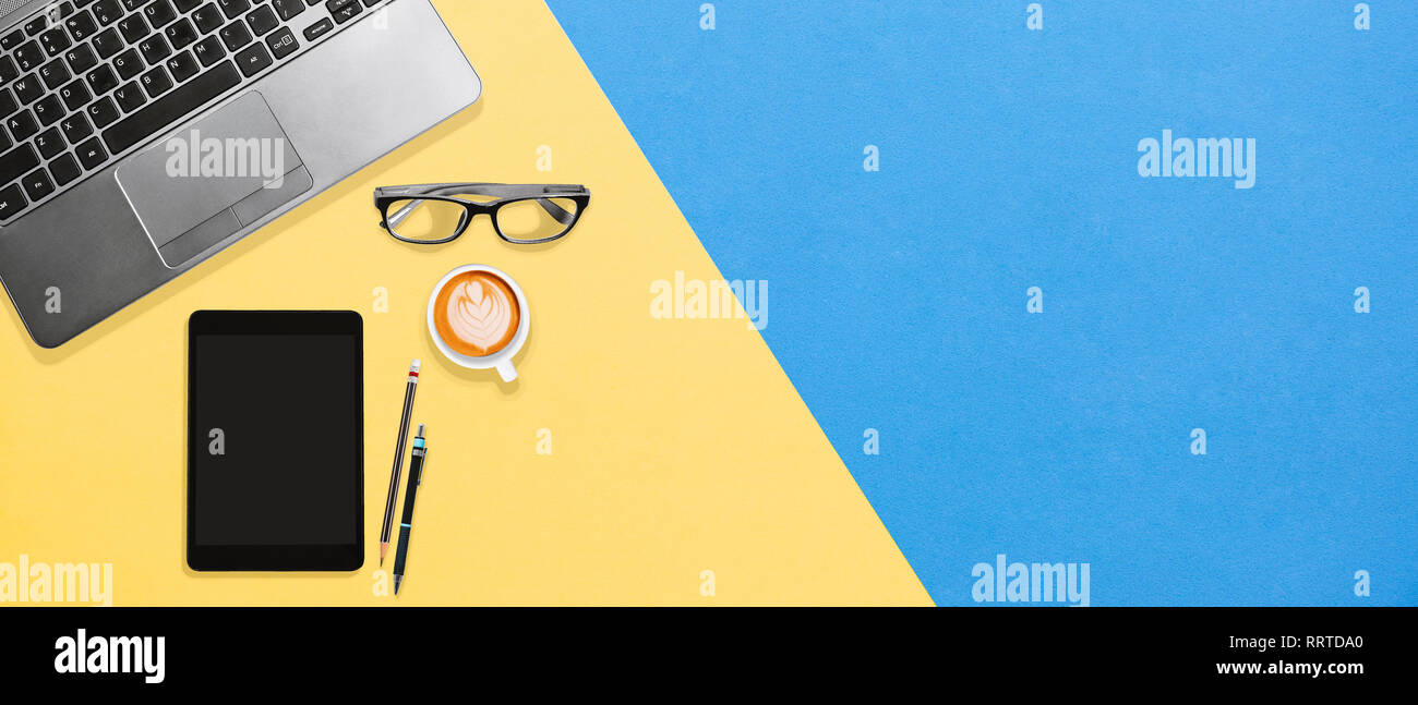 Colorful office desktop workspace with laptop, tablet, eyeglasses and a ...