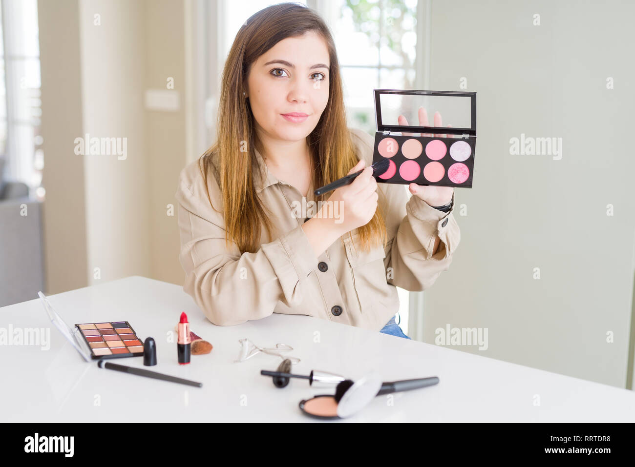 Beautiful young woman using make up cosmetics applying color from ...