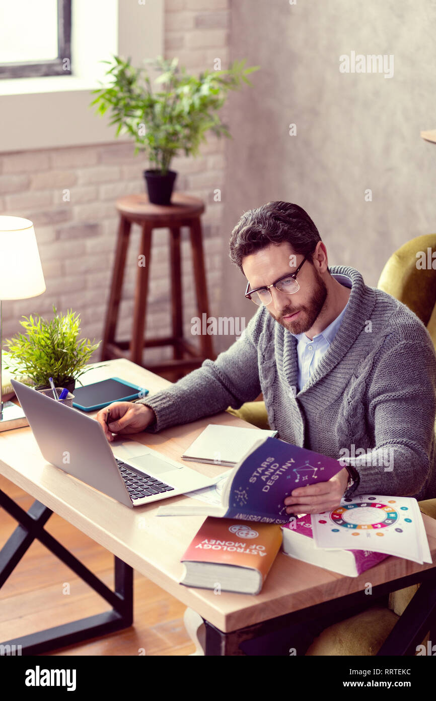 Nice smart man reading the book on astrology Stock Photo - Alamy