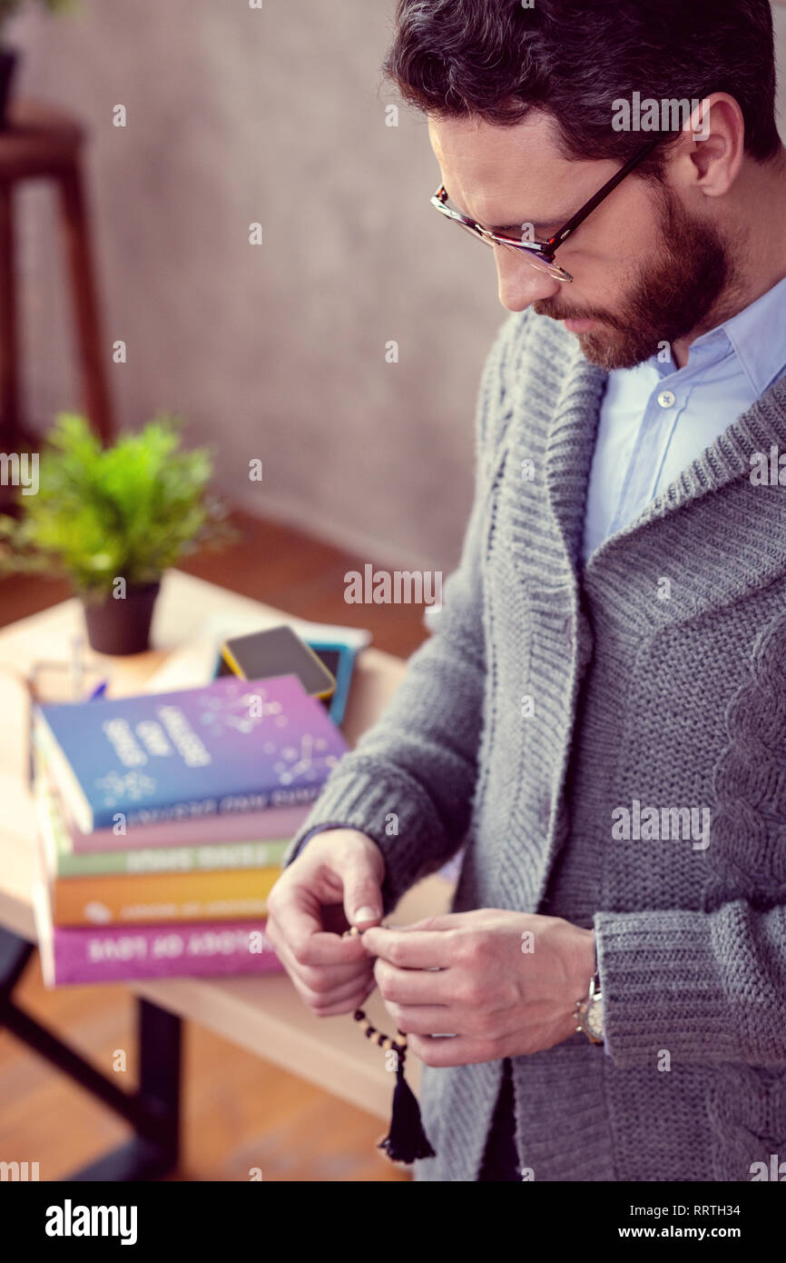 Nice serious man looking at the string of beads Stock Photo - Alamy