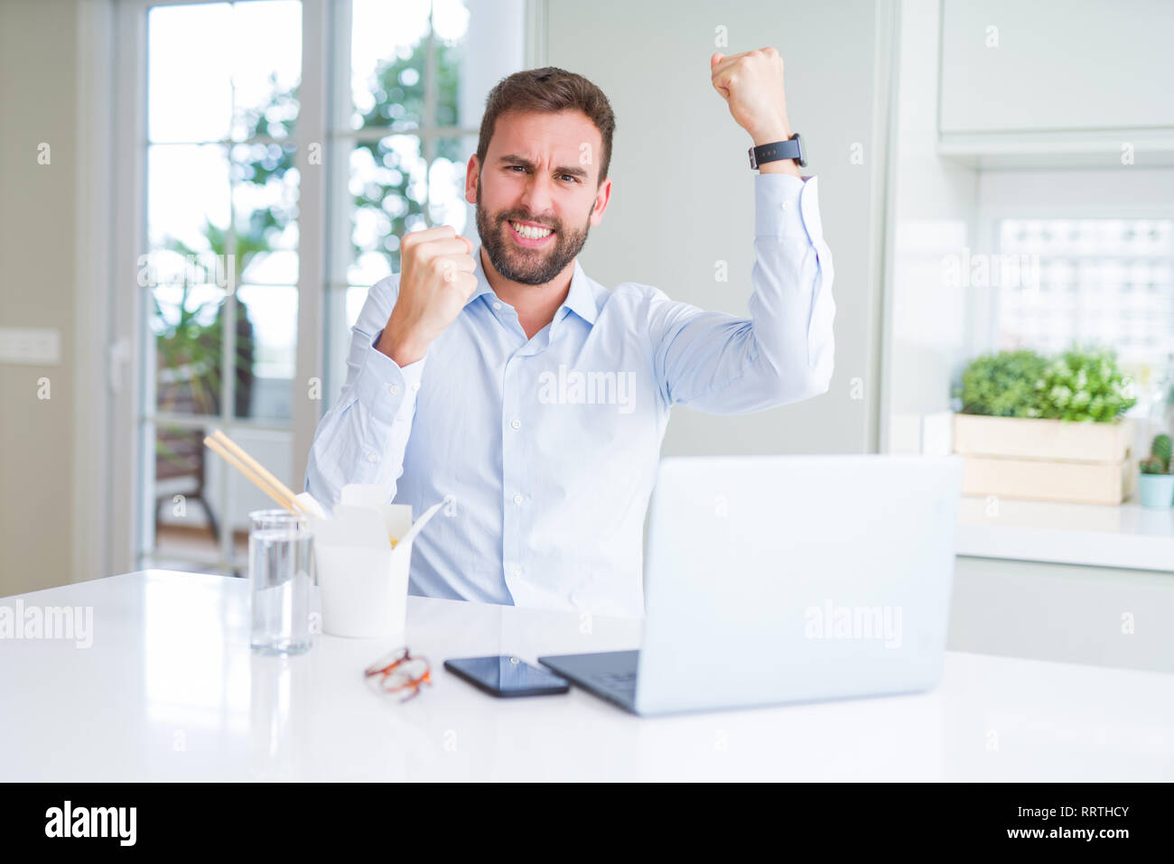 Business man eating take away asian noodles food while working using ...