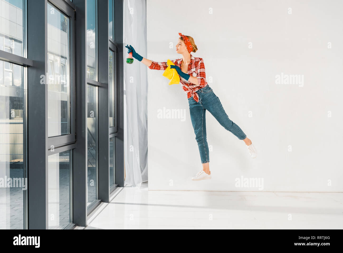 floating girl in jeans and plaid shirt cleaning windows with rag and ...