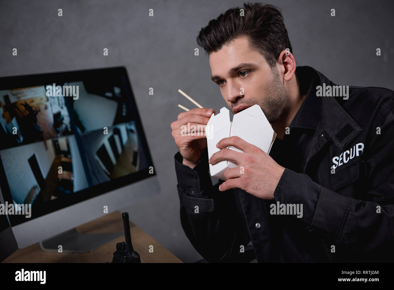 guard in uniform eating junk food and looking at computer monitor Stock ...