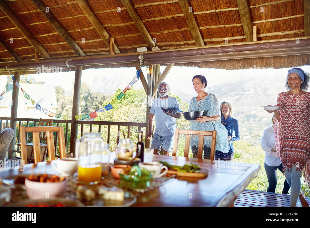 Friends carrying healthy food to table in hut during yoga retreat Stock ...