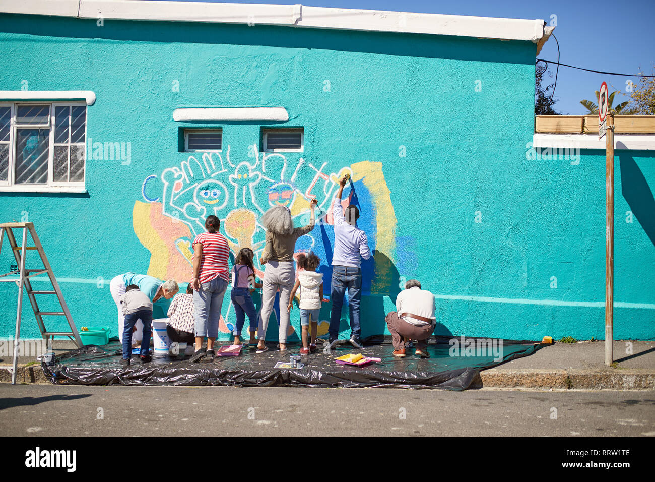 Community volunteers painting vibrant mural on sunny urban wall Stock ...