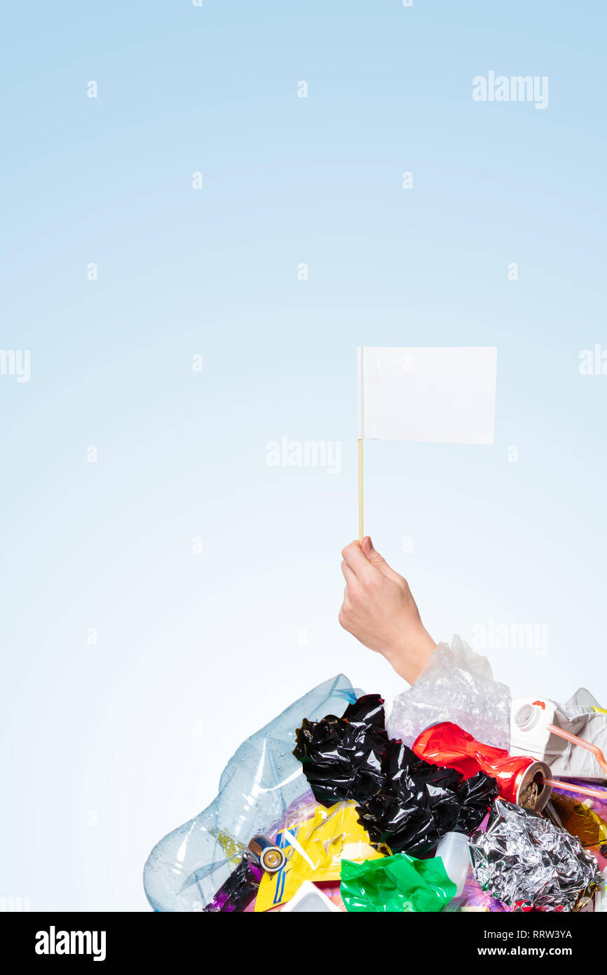 An earth globe covered with trash and male hand holding white flag over ...