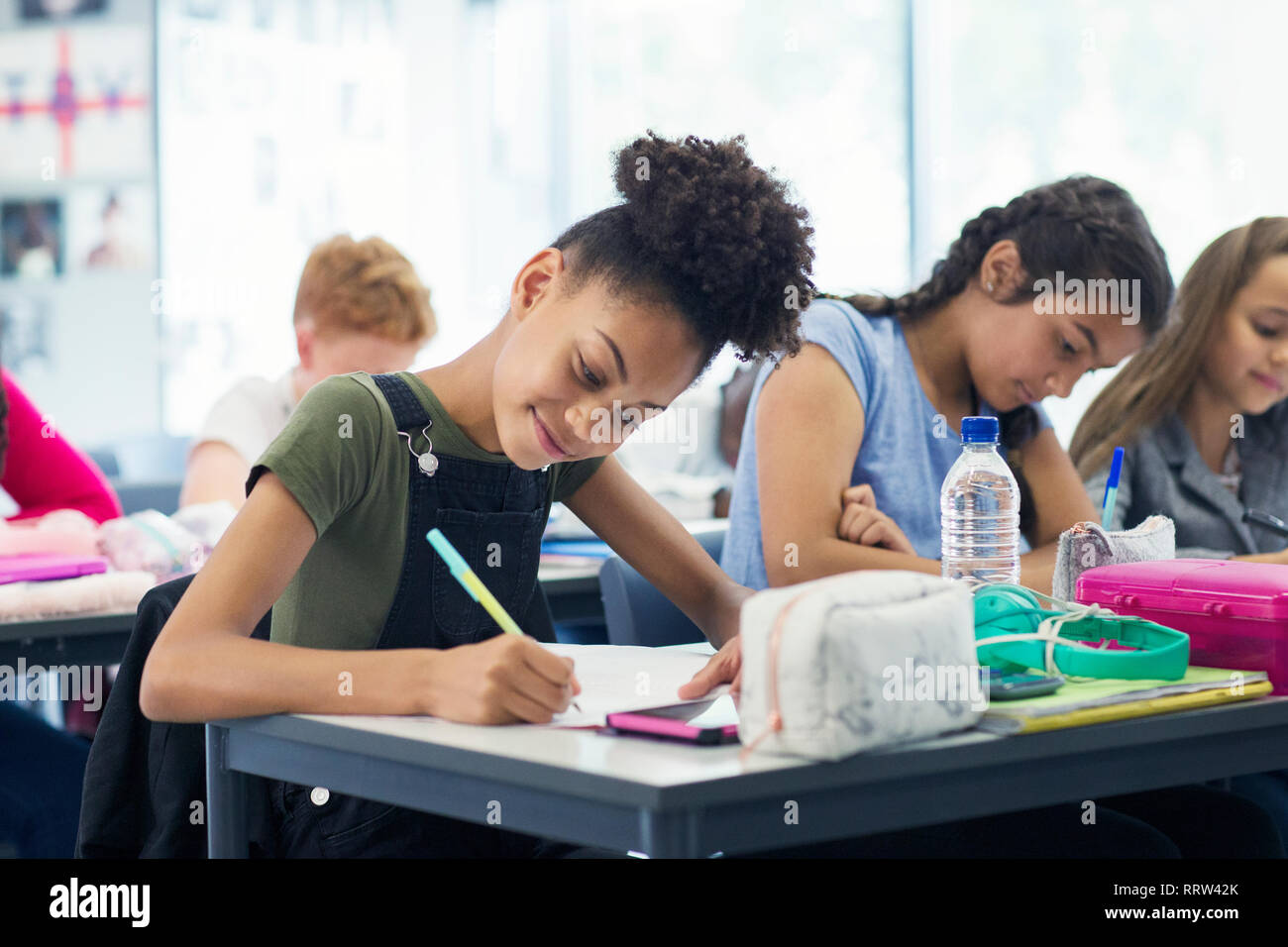 Confident junior high school girl student doing homework in classroom ...