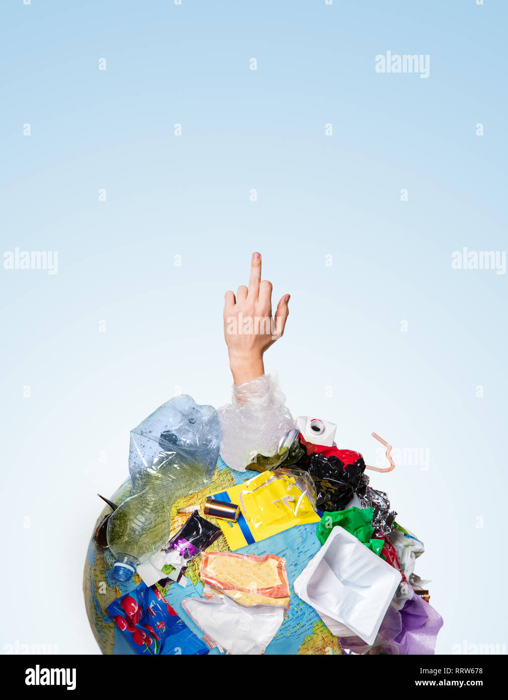 An earth globe covered with trash and male hand showing middle finger ...