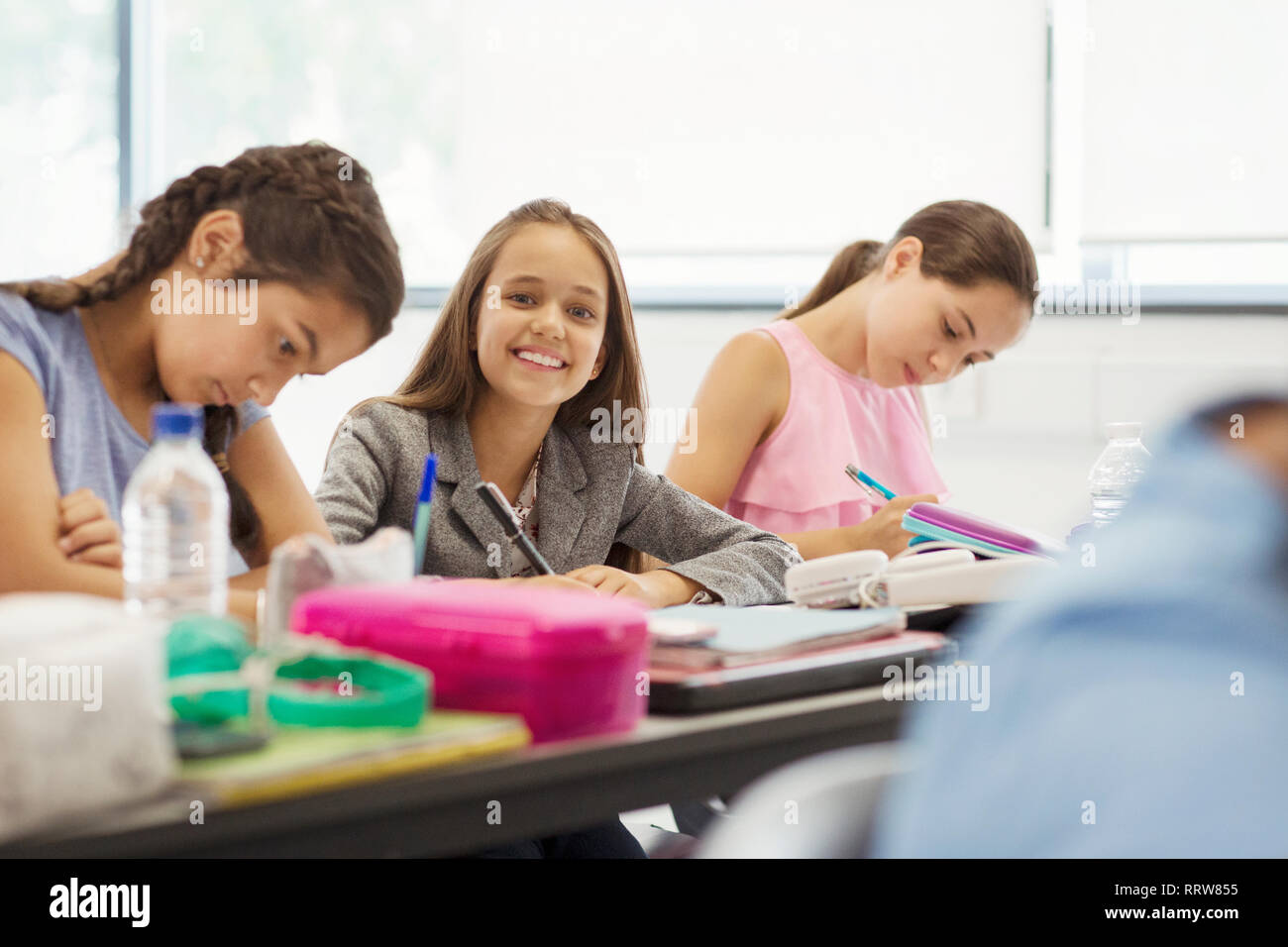 Portrait smiling, confident junior high school girl student studying in ...