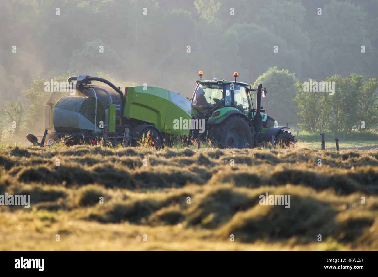 Farmer with tractor in field, making hay Stock Photo - Alamy