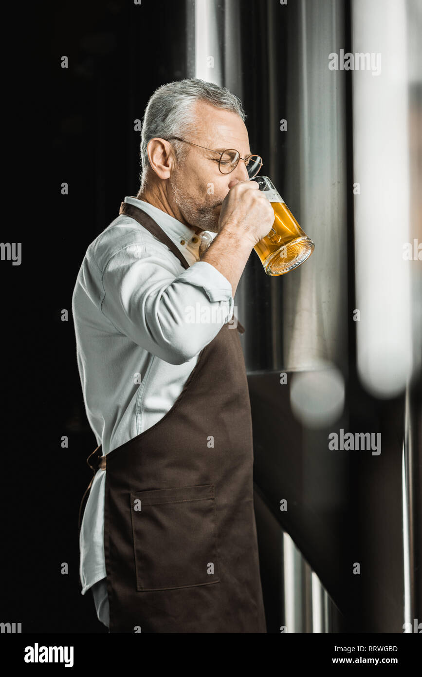 handsome male brewer drinking beer from glass in brewery Stock Photo ...