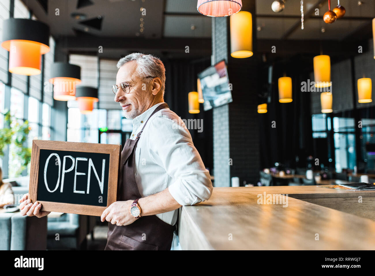 owner of pub holding open sign and standing near bar counter Stock ...