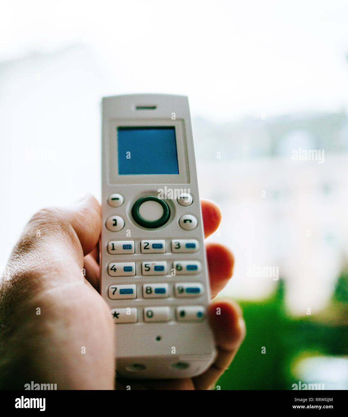 man hand holding outdoor home office white cordless phone dialing a ...