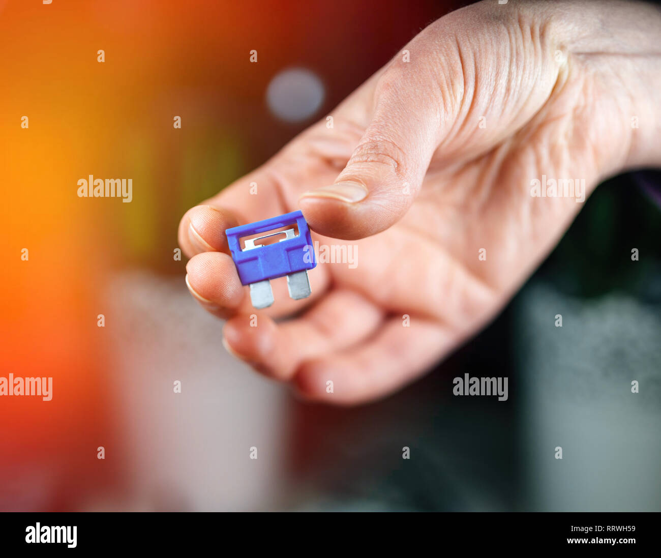 Woman hand holding blue amp rated car fuses before inserting them fuse ...