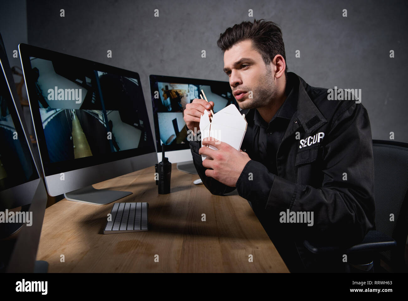 guard eating junk food and looking at computer monitor Stock Photo - Alamy