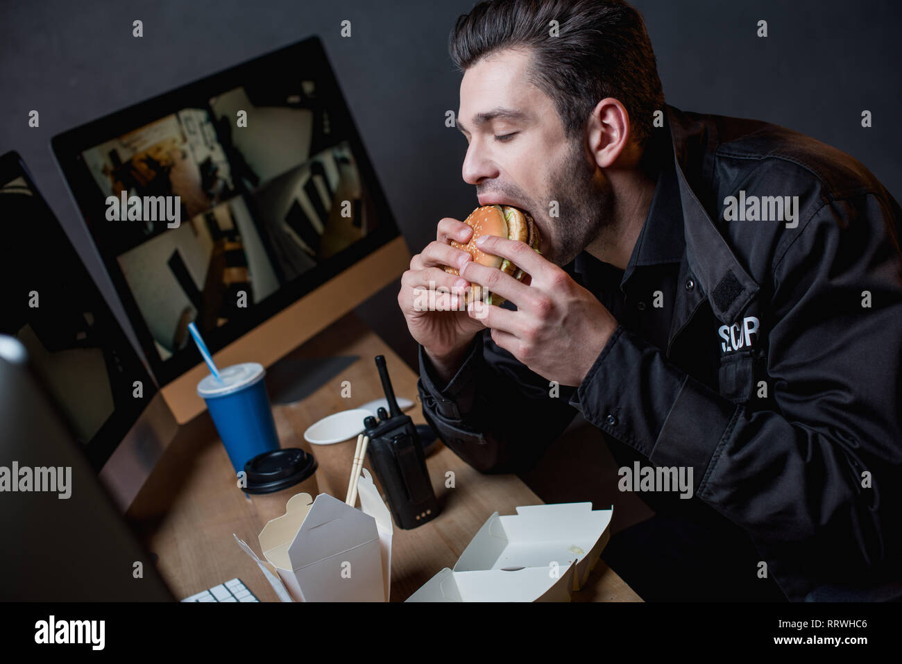 guard in black uniform eating burger at workplace Stock Photo - Alamy