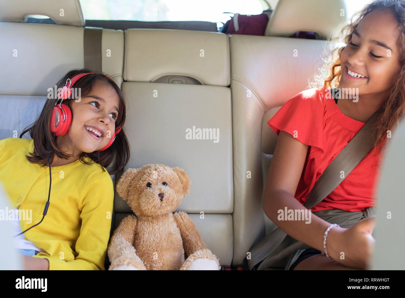 Happy sisters and teddy bear riding in back seat of car Stock Photo - Alamy