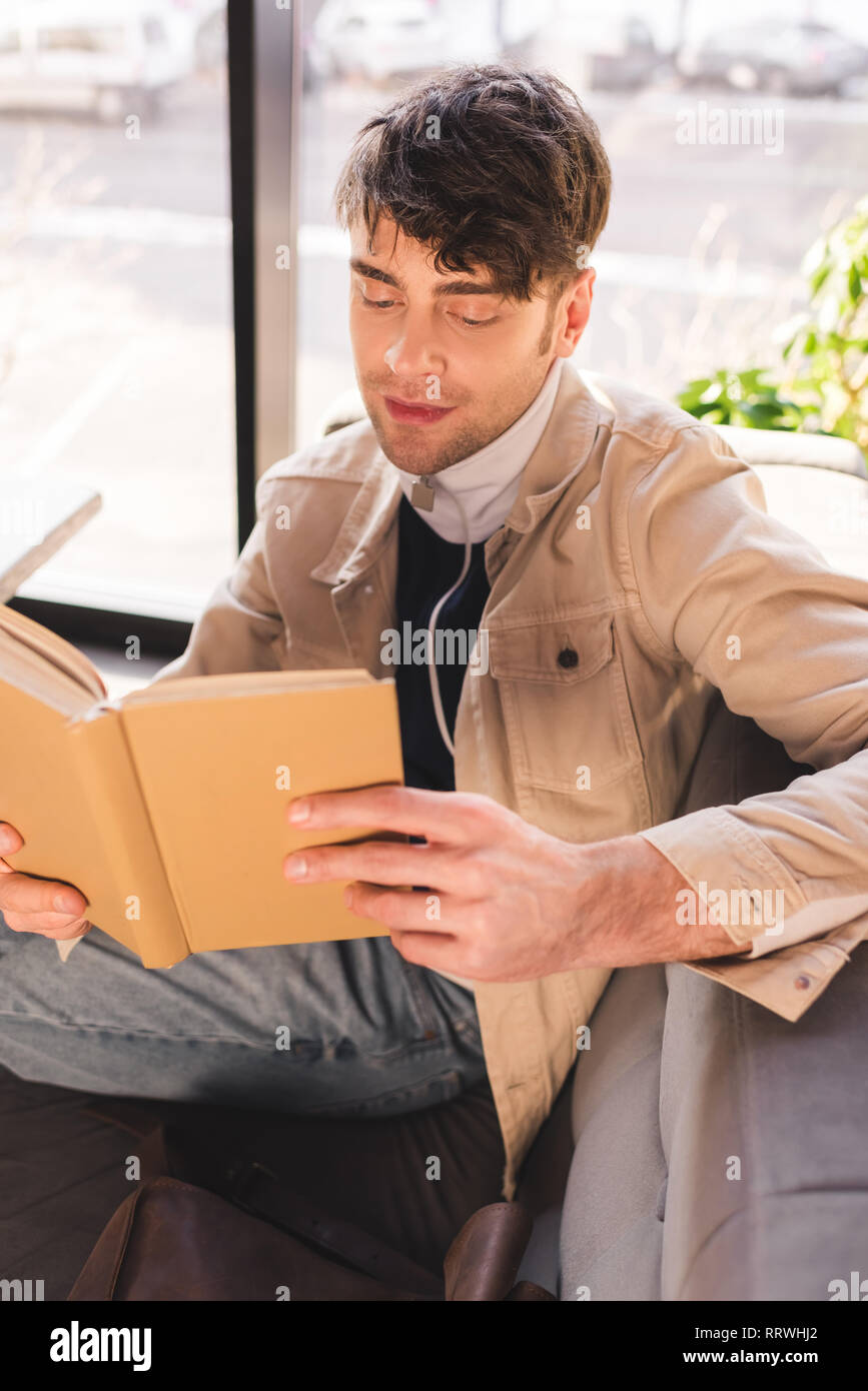 happy man smiling while reading book in cafe Stock Photo - Alamy