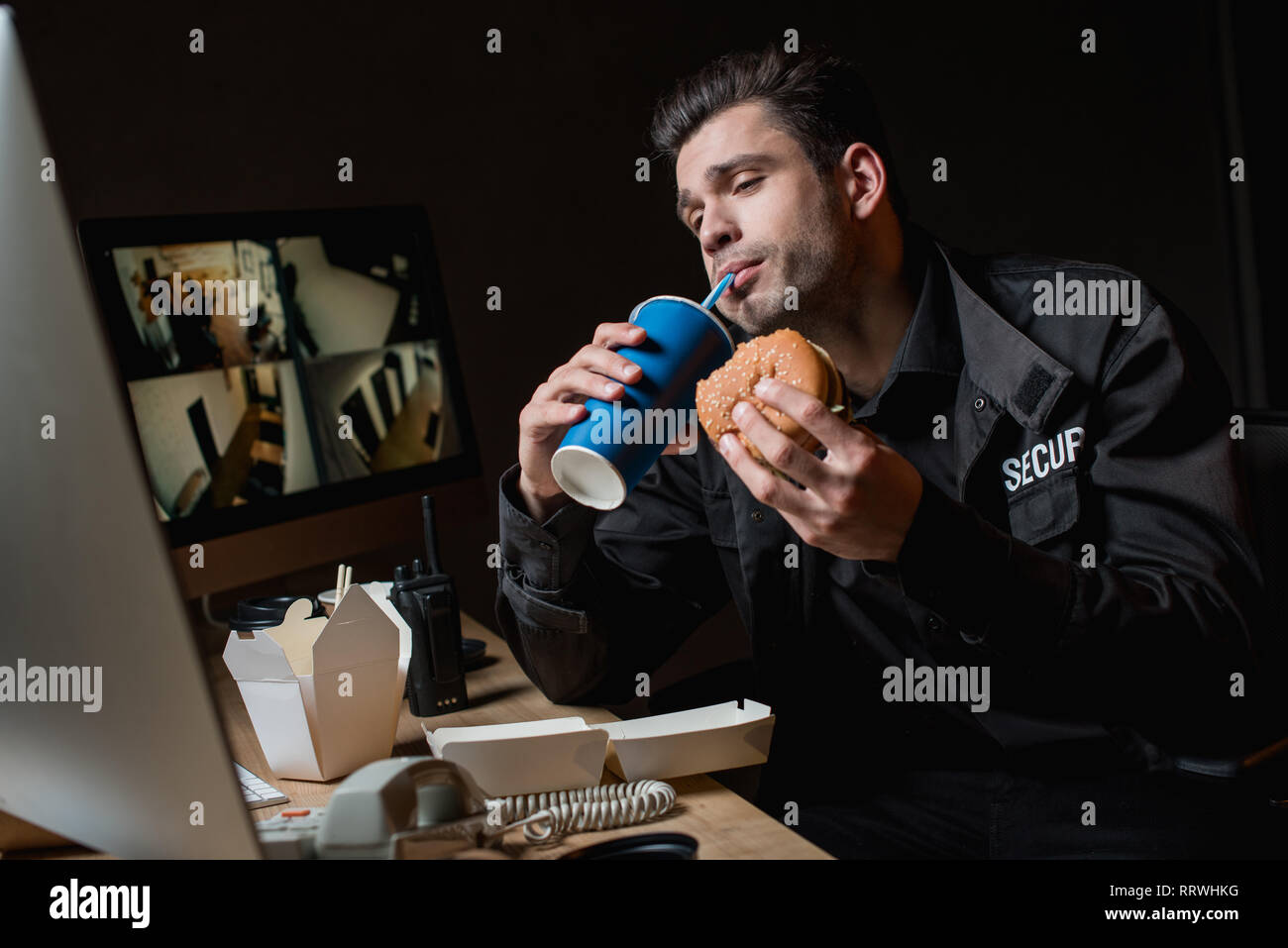 handsome guard drinking and eating burger at workplace Stock Photo - Alamy