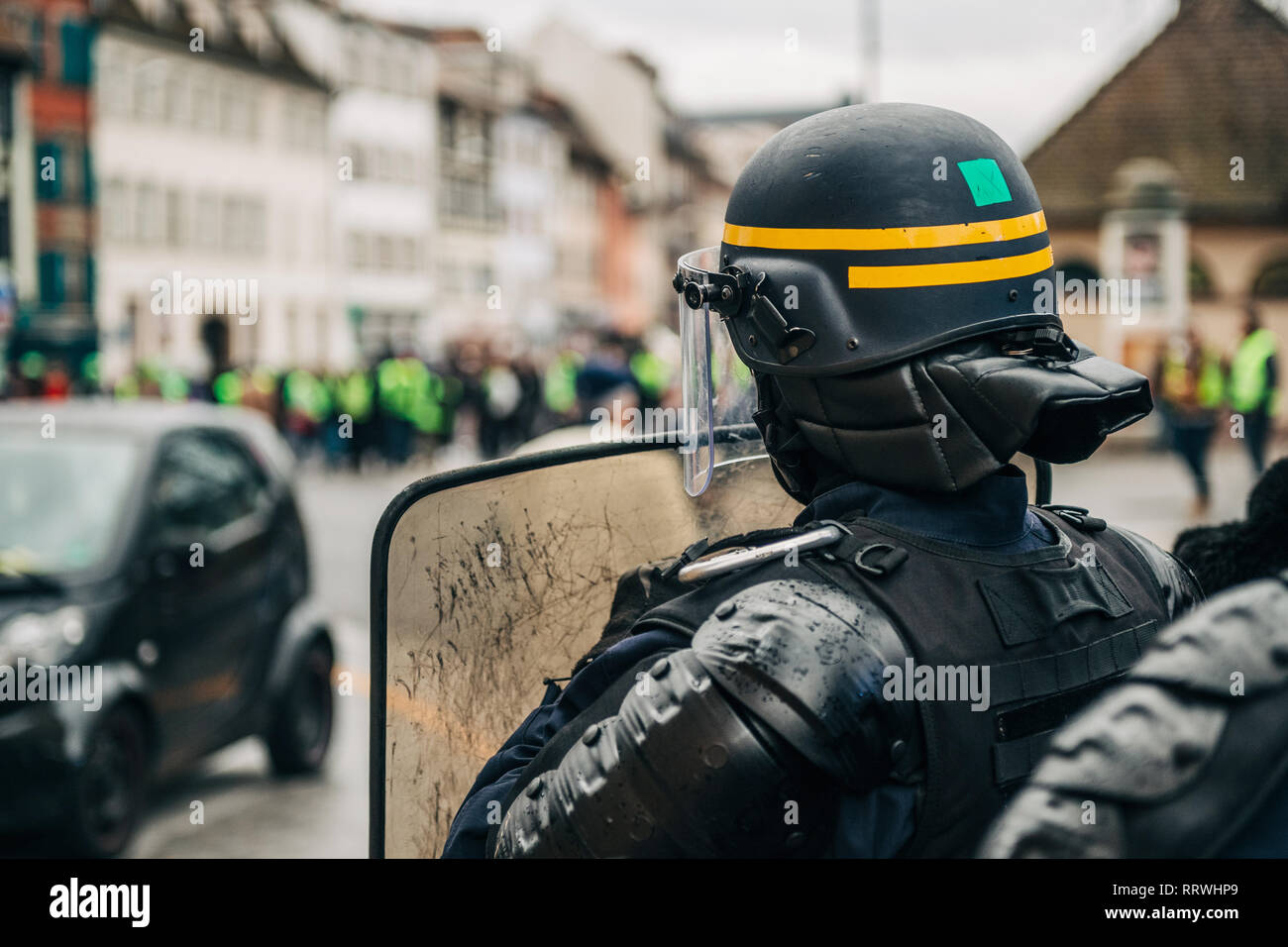 Rear view of police officer wearing helmet and shield securing the zone ...