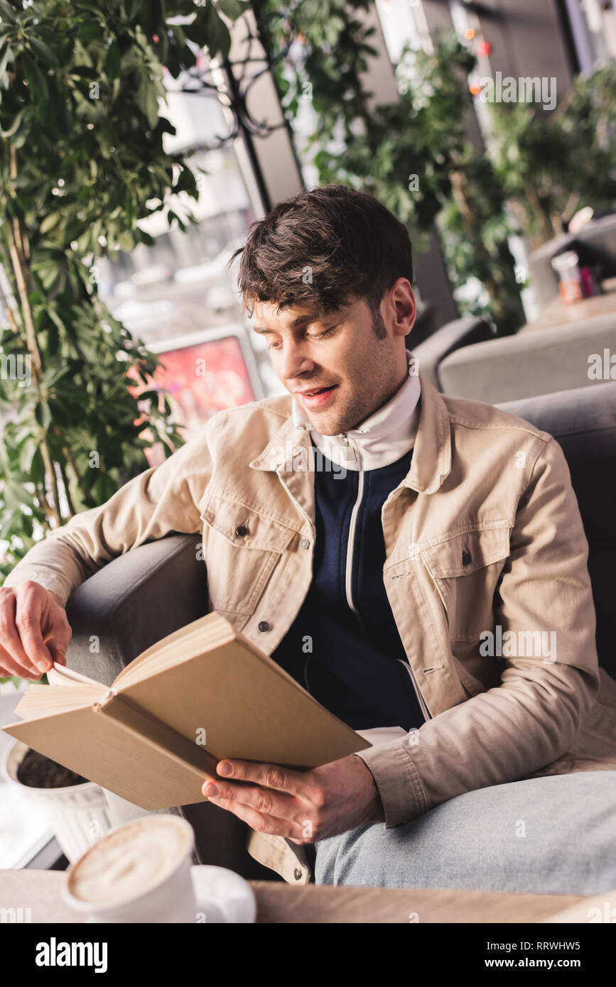 happy man reading book near cup with cappuccino in cafe Stock Photo - Alamy