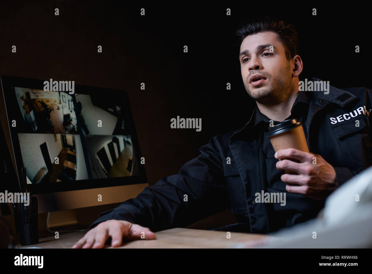 guard holding paper cup and looking at computer monitor Stock Photo - Alamy