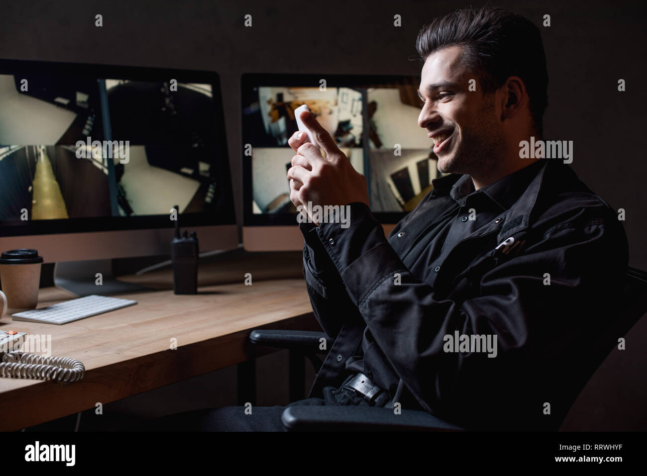 smiling guard in uniform using smartphone at workplace Stock Photo - Alamy
