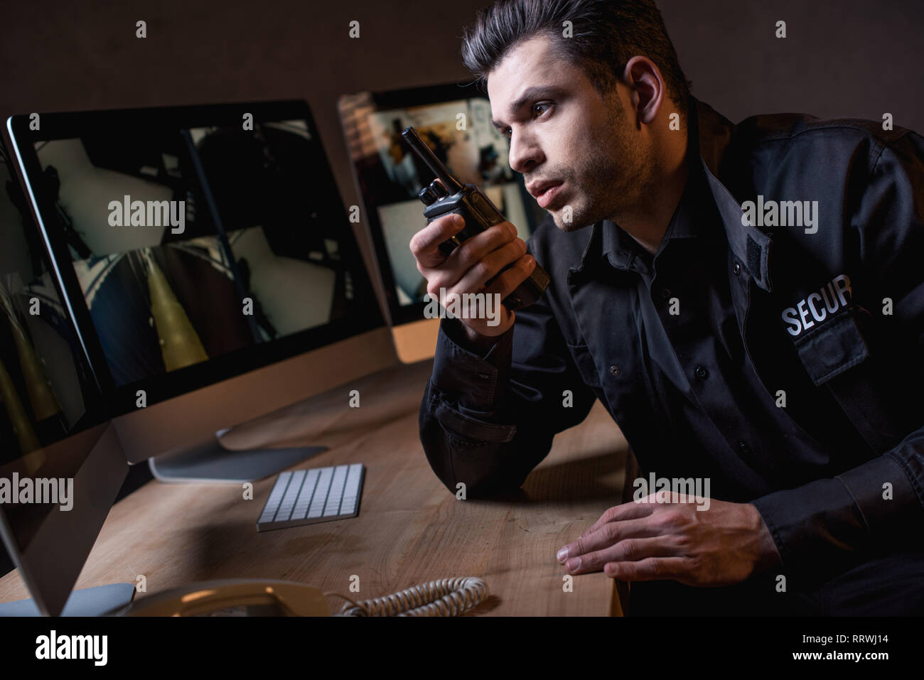 handsome guard in uniform talking on walkie-talkie at workplace Stock ...