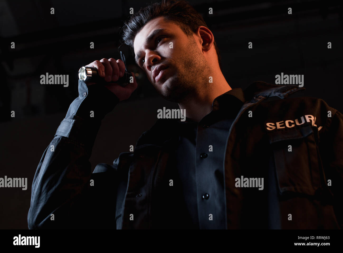 guard in uniform holding flashlight and looking away Stock Photo - Alamy
