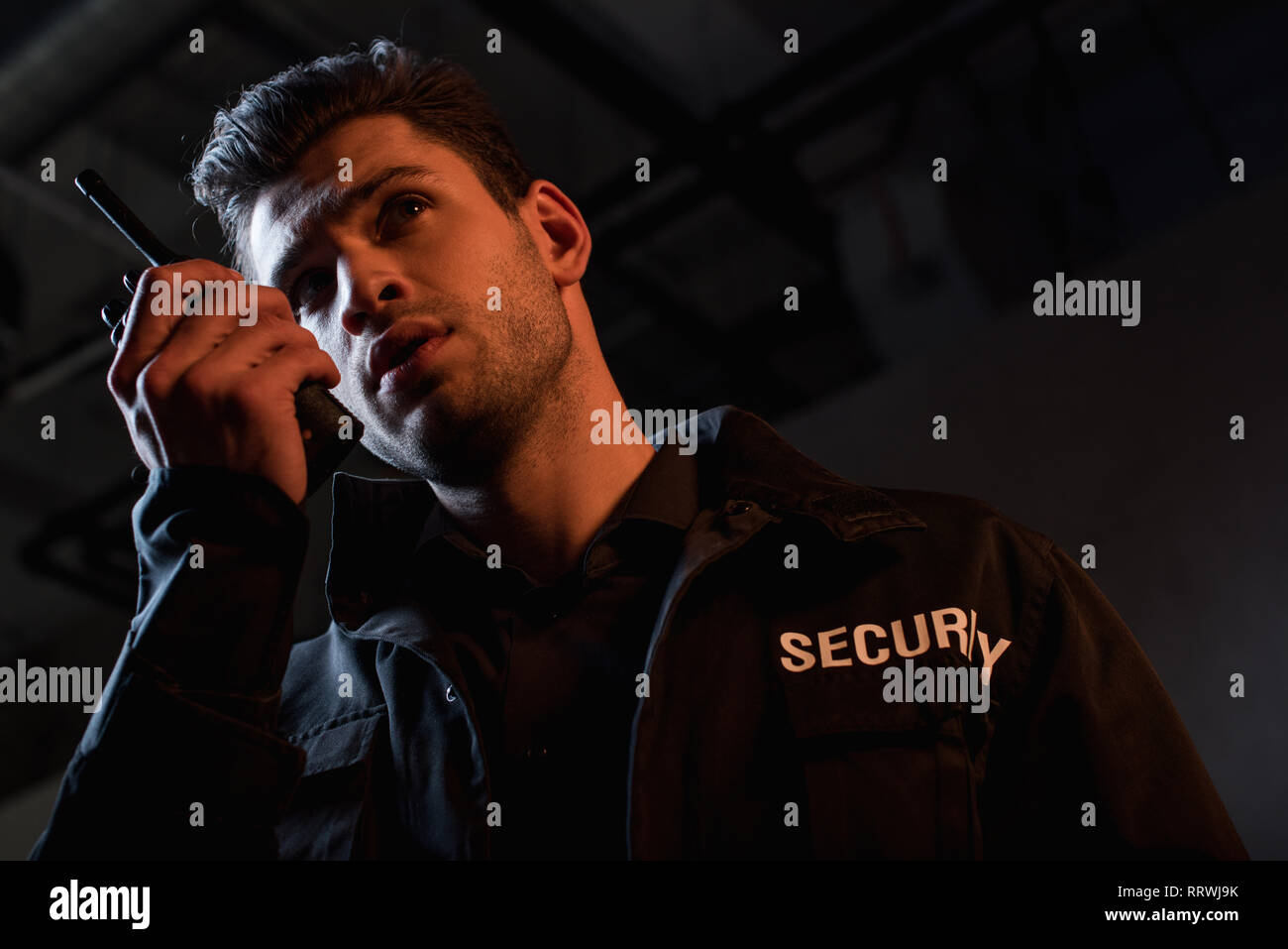 handsome guard in uniform using walkie-talkie and looking away Stock ...