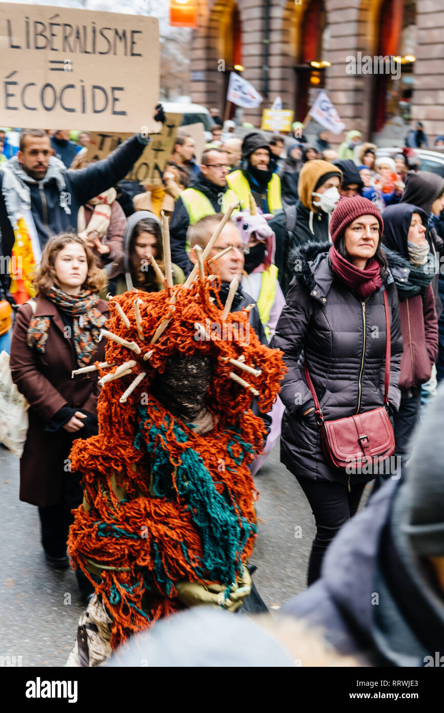 STRASBOURG, FRANCE - DEC 8, 2018: Crowd marching near woman in strange ...