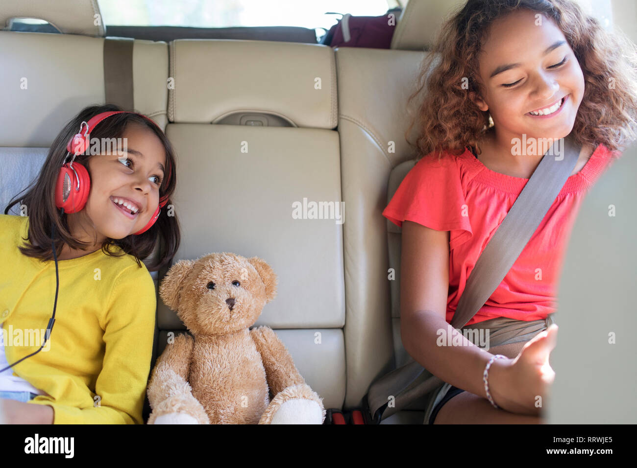 Happy sisters and teddy bear riding in back seat of car Stock Photo - Alamy