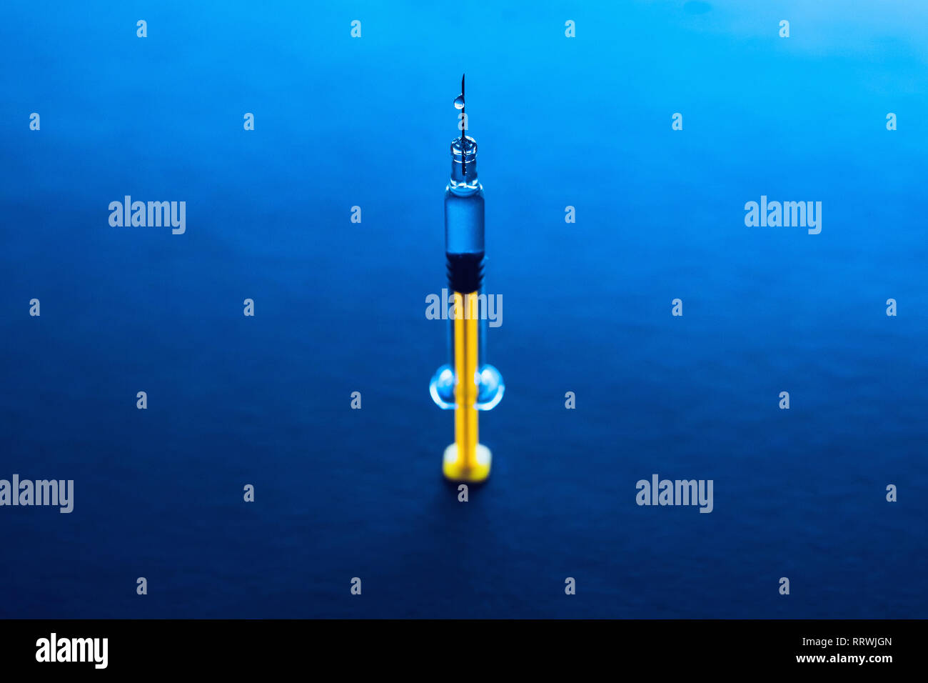 Yellow glass medical syringe over dark background Stock Photo - Alamy