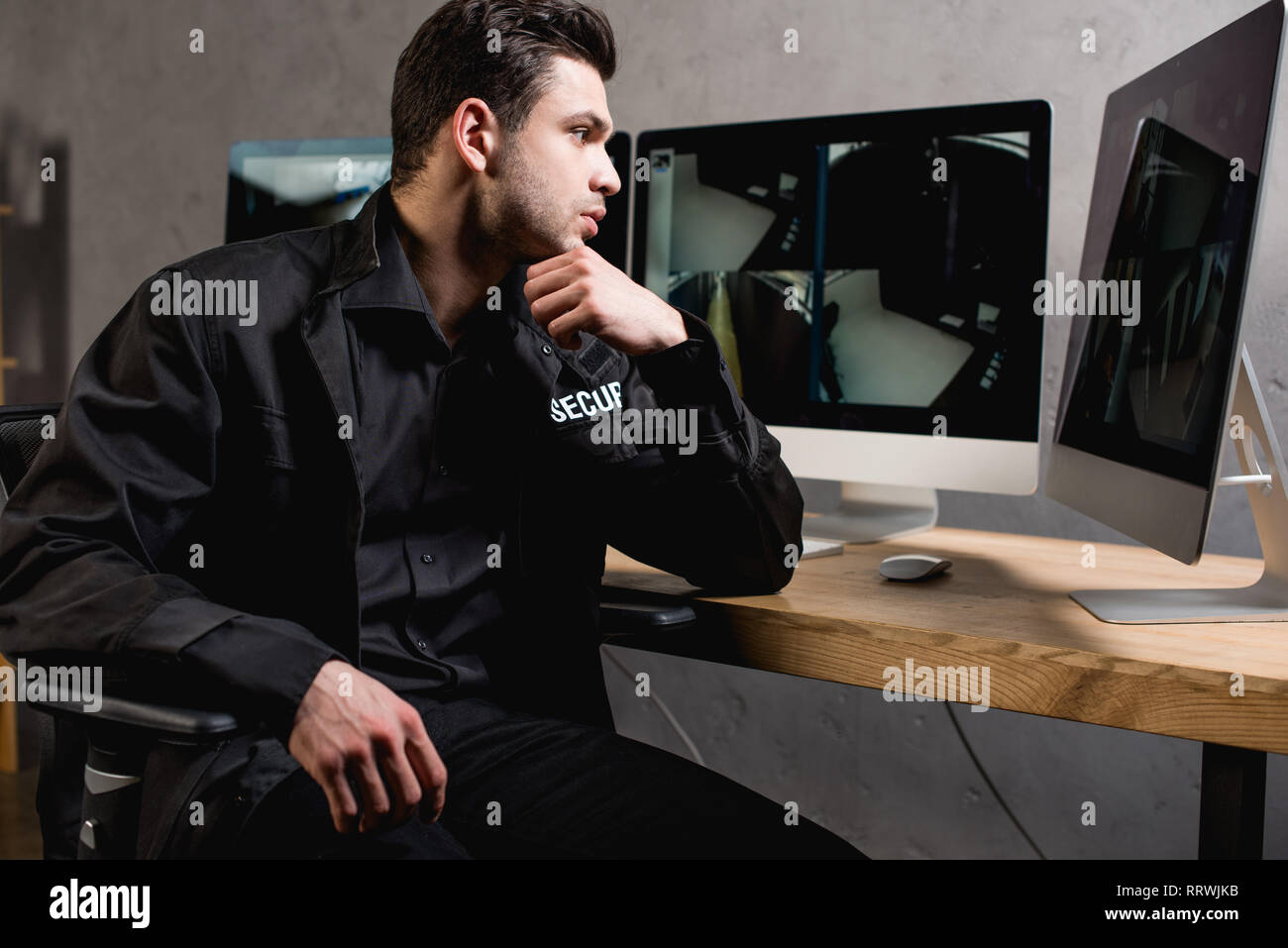 concentrated guard in uniform looking at computer monitor at workplace ...