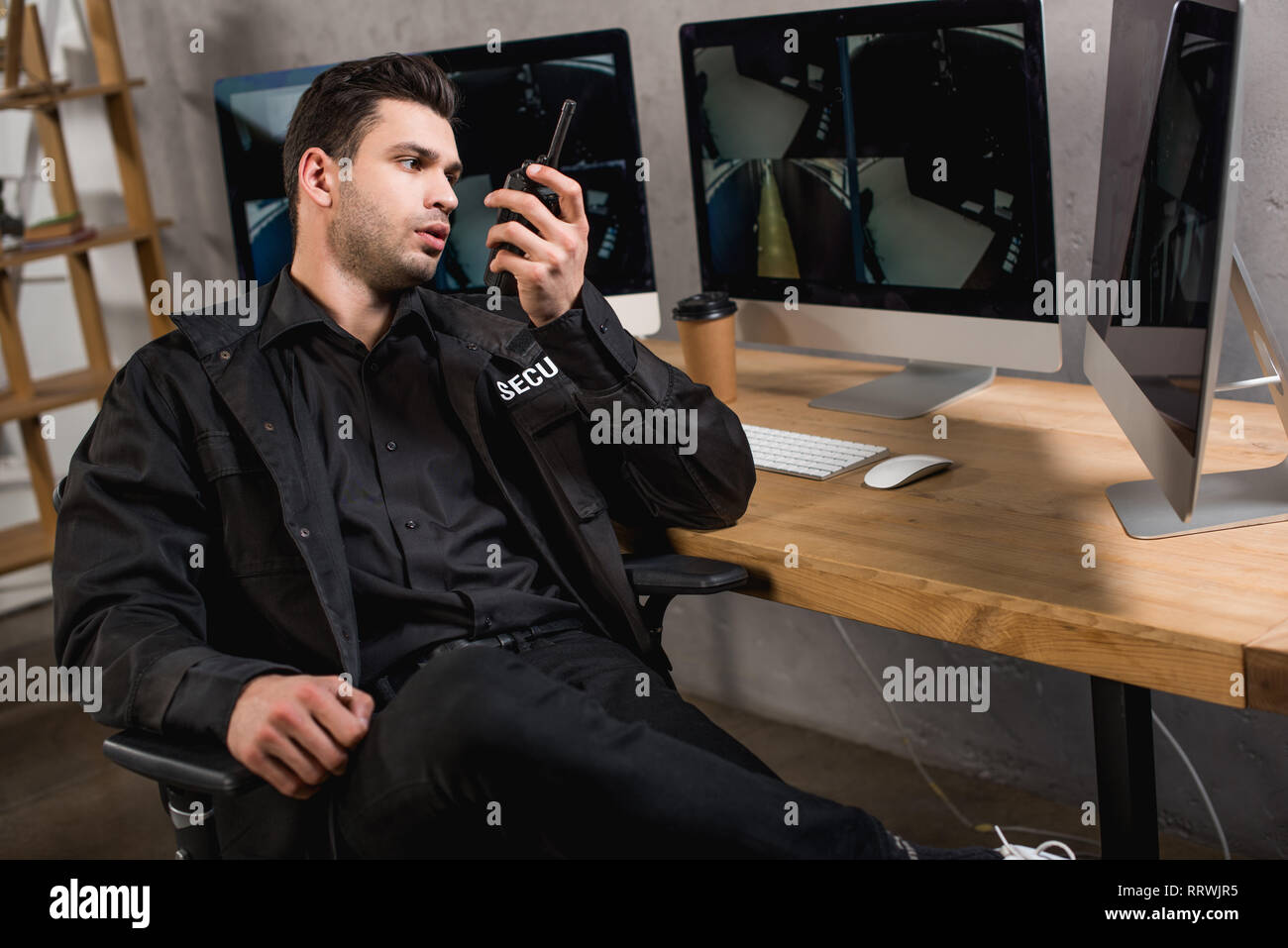 handsome guard in uniform talking on walkie-talkie at workspace Stock ...