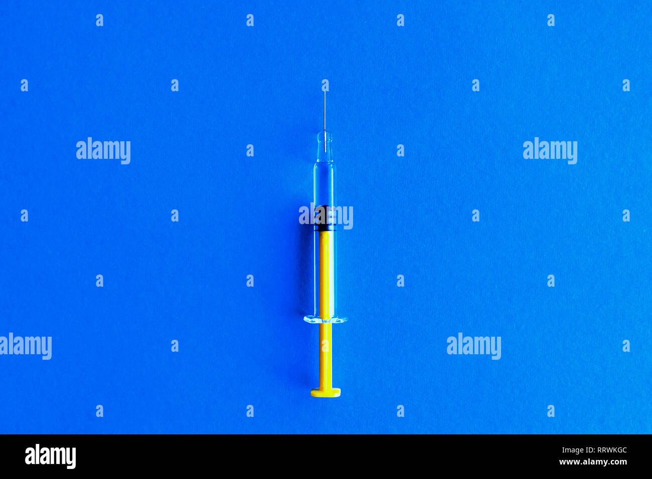 Yellow glass medical syringe over blue background Stock Photo - Alamy